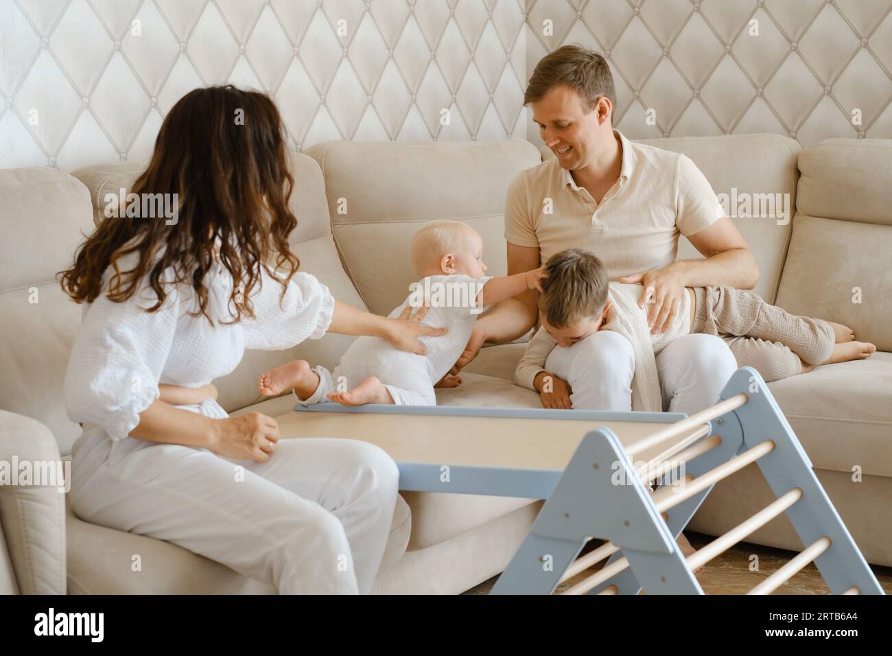Family with two kids on the couch having fun. Mather, father baby and ...