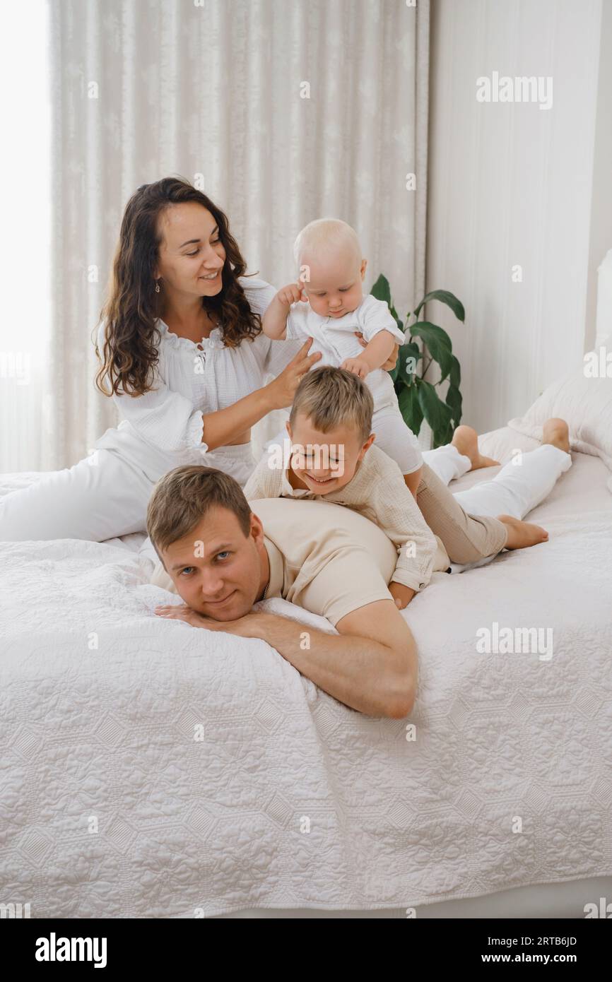 Family with two kids on the bed having fun. Mather, father baby and ...