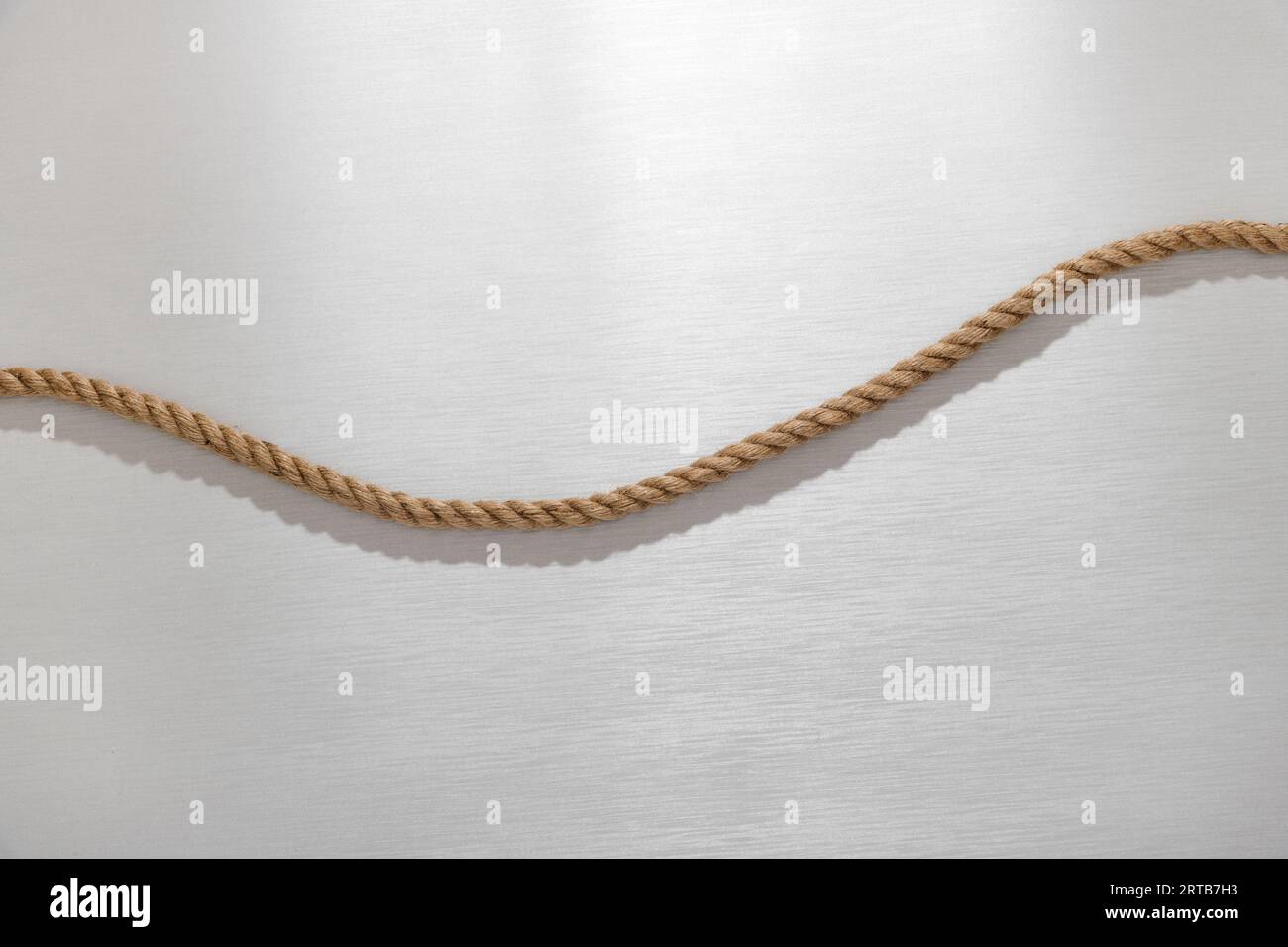 Top view of curved natural jute rope placed on gray table in sunlight ...