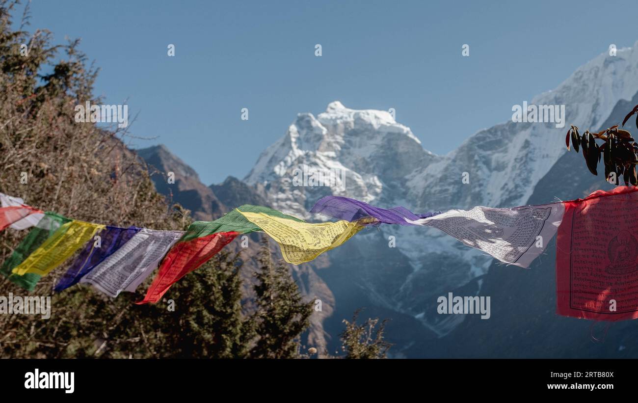 A range of colorful flags blowing in the wind against a mountain ...