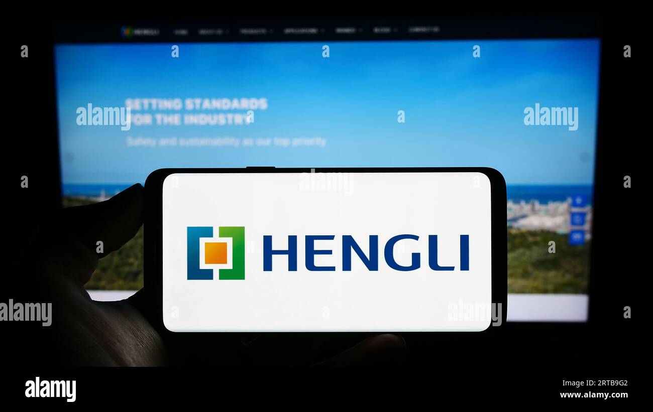 Person holding cellphone with logo of Chinese petrochemical company Hengli Group on screen in ...