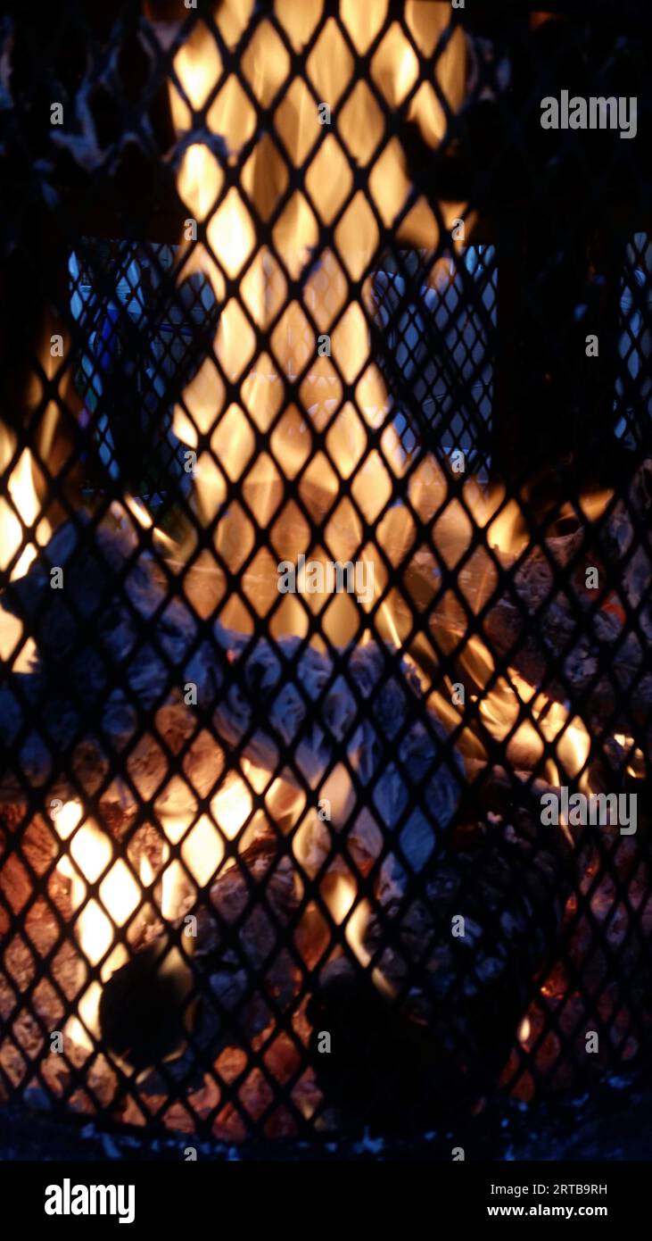 A lit grill with flames emanating from the coal bed, illuminated by a ...
