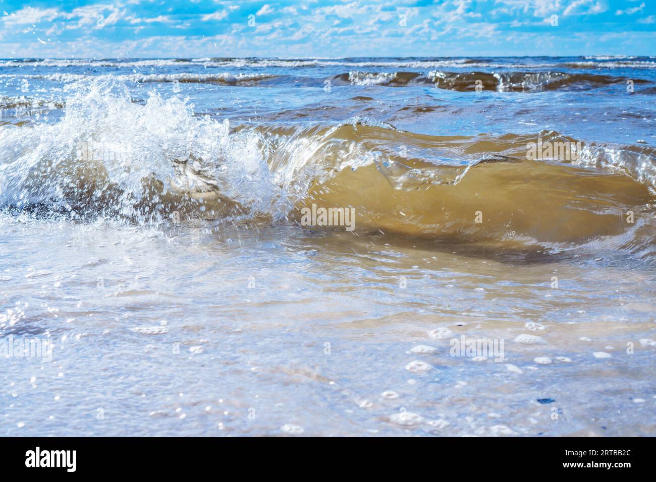 Close-up of blue water, foamy waves of sea ocean on windy day. Sun rays ...