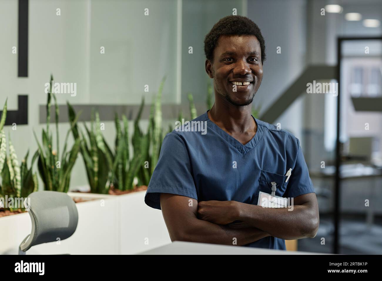 Young smiling African American clinics receptionist with crossed arms ...