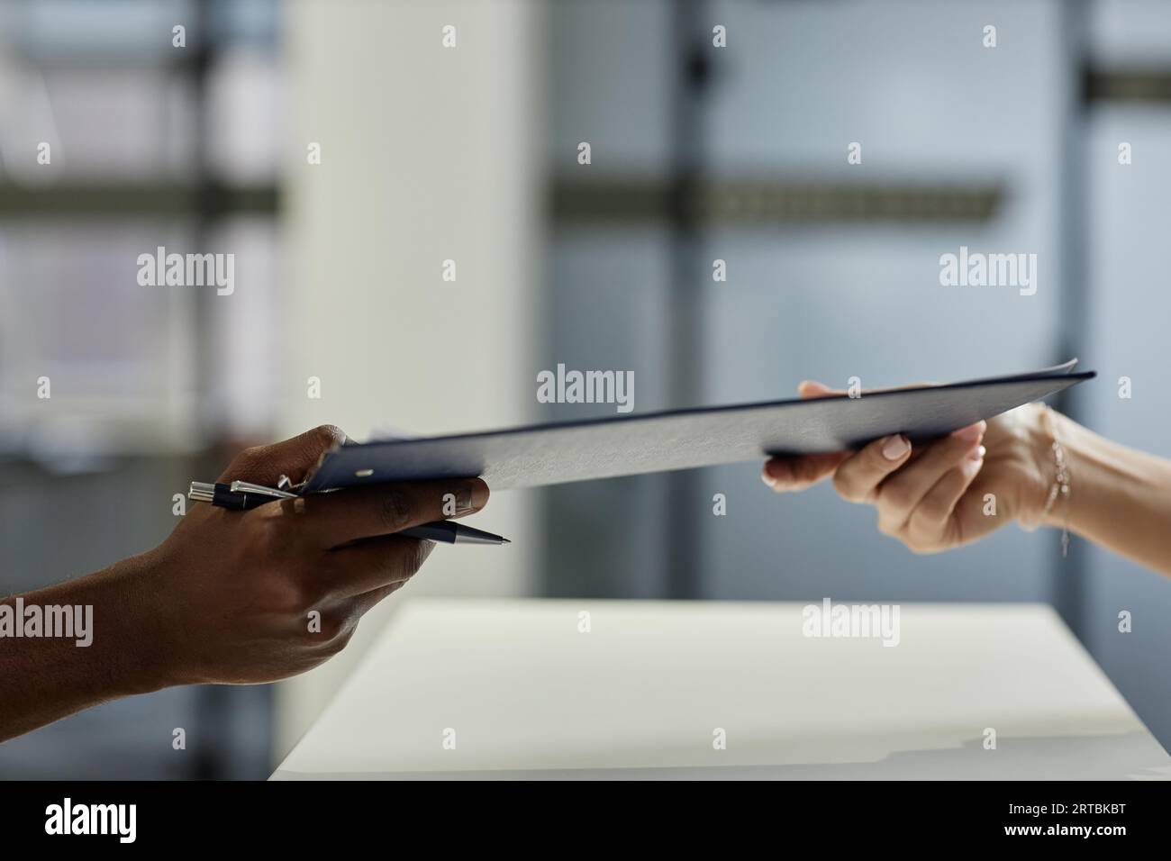 Side view of hand of young female patient passing clipboard with ...