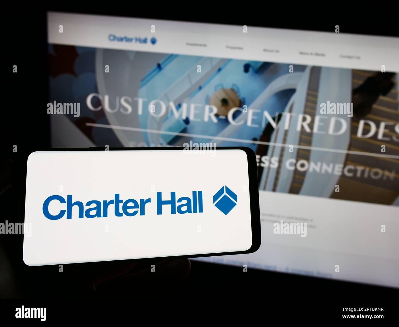 Person holding mobile phone with logo of real estate company Charter ...