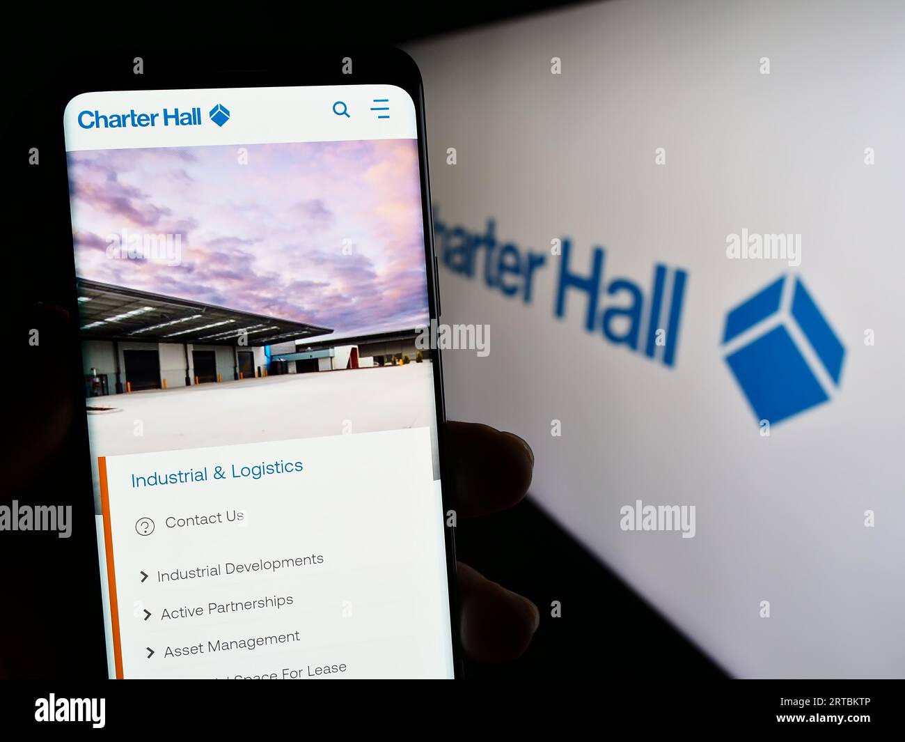 Person holding mobile phone with web page of real estate company ...