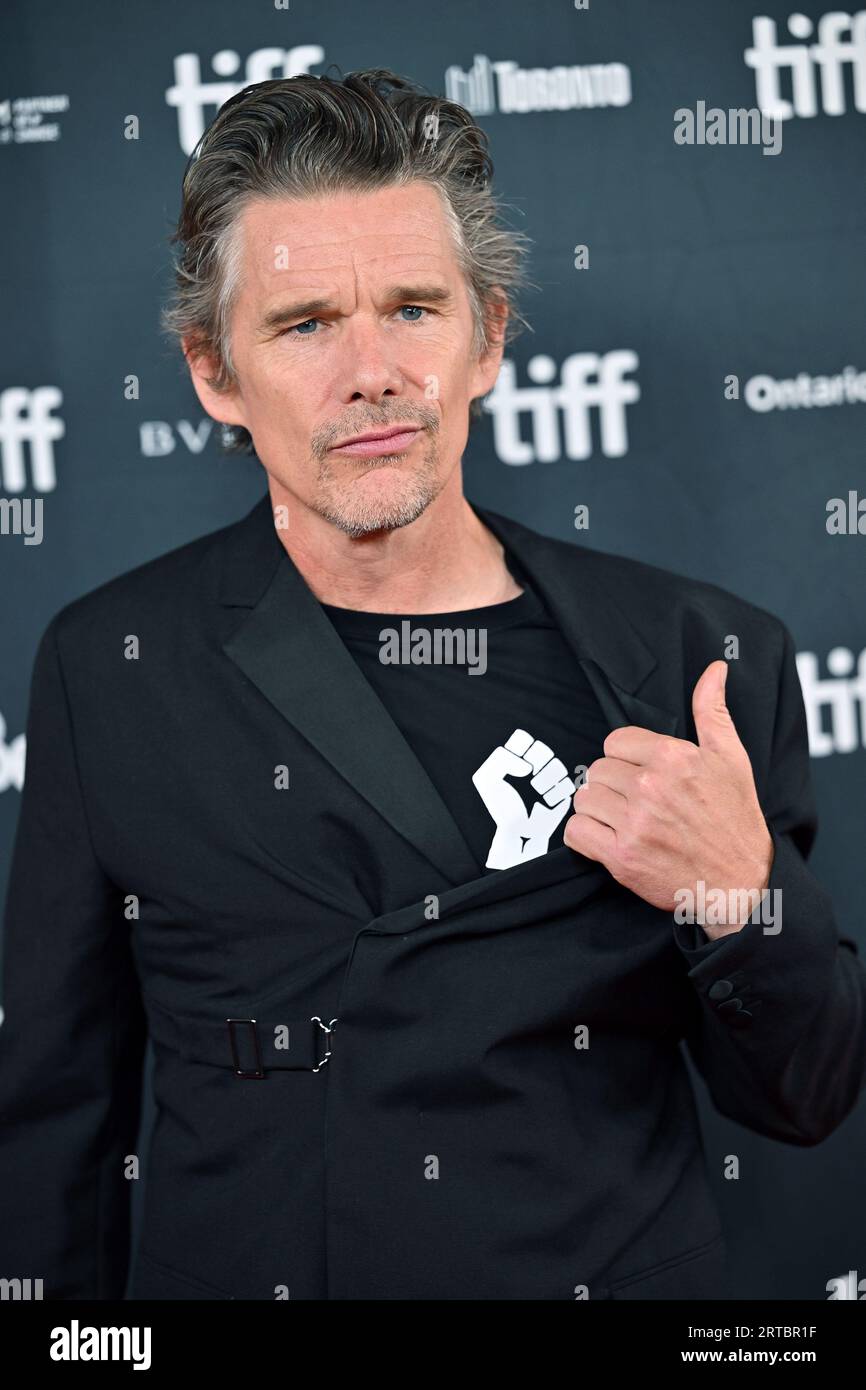 Toronto, Canada. 11th Sep, 2023. Ethan Hawke lifts his jacket to reveal ...