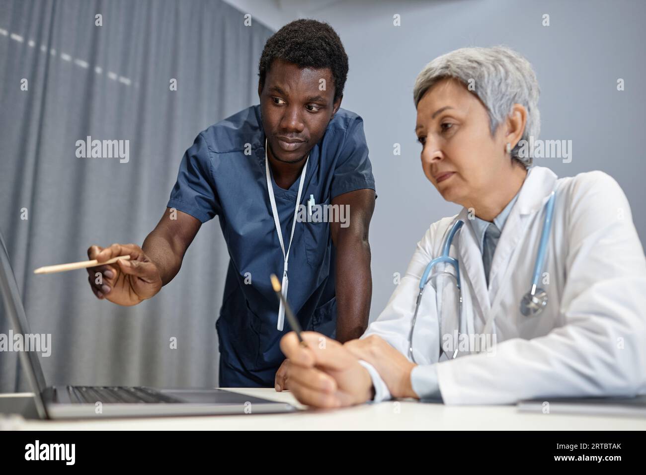 Young African American assistant of general practitioner pointing at ...