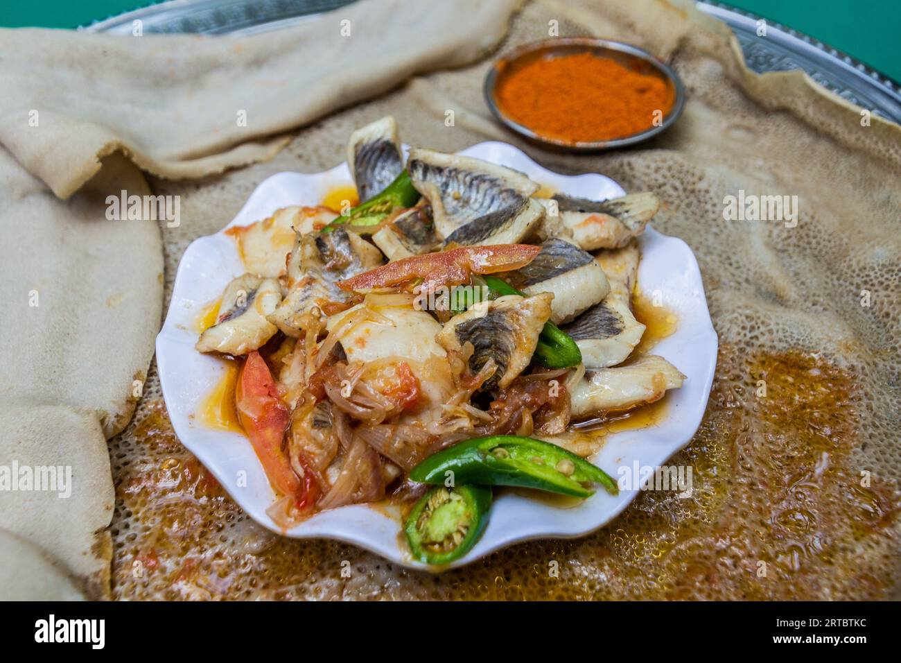 Meal in Ethiopia - pieces of fish with chilli peppers and vegetables on ...