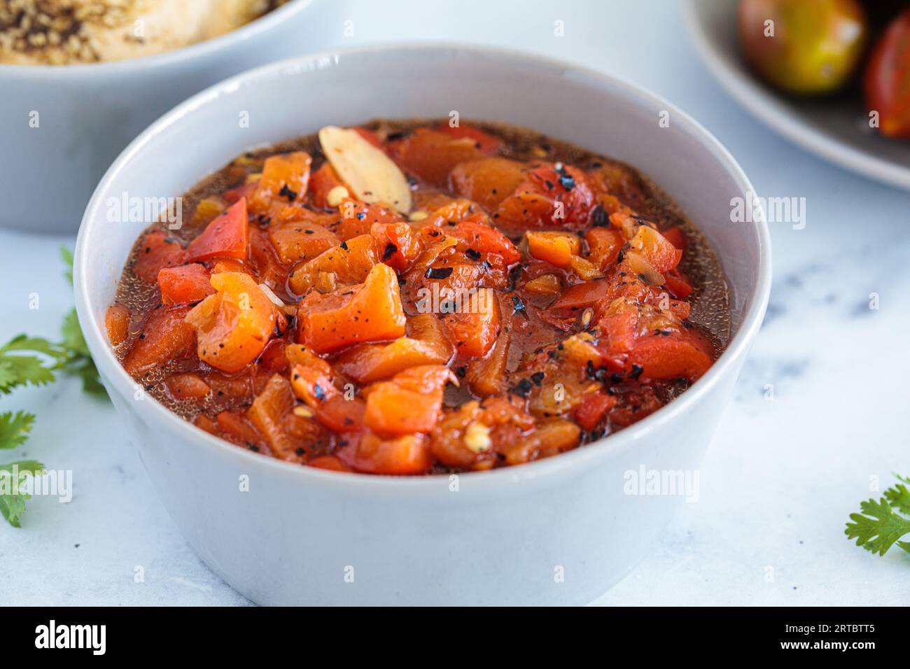 Roasted red pepper salad with garlic in gray bawl, close-up. Israeli ...
