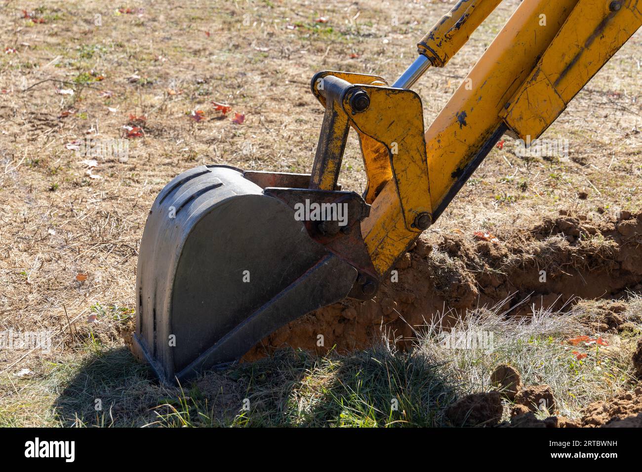 Excavator digging a narrow trench ditch for a building foundation Stock ...
