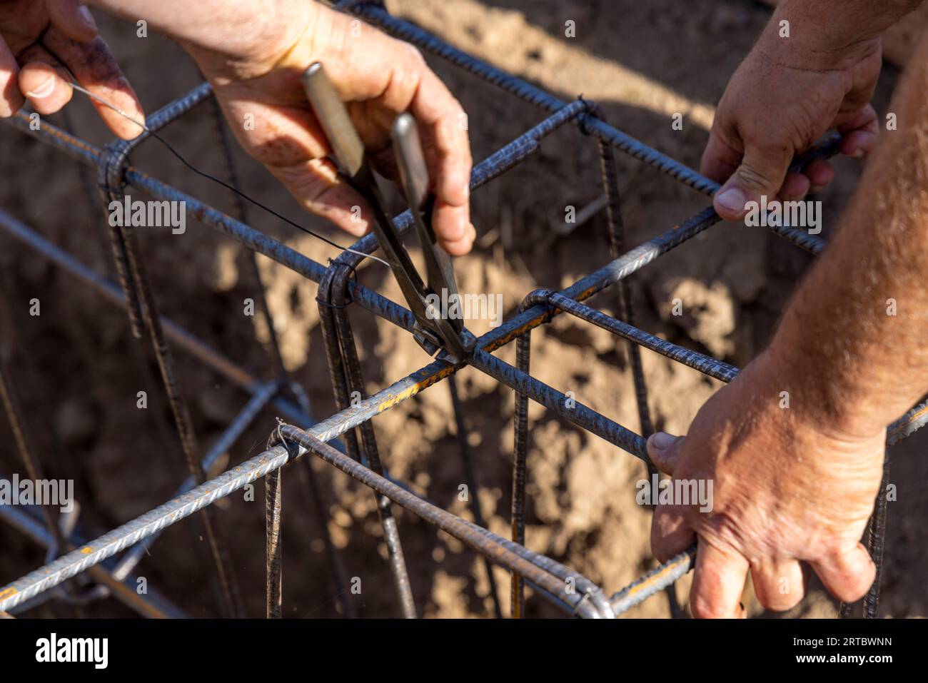 Two workers reinforcing a formwork rebar for foundations of a building ...