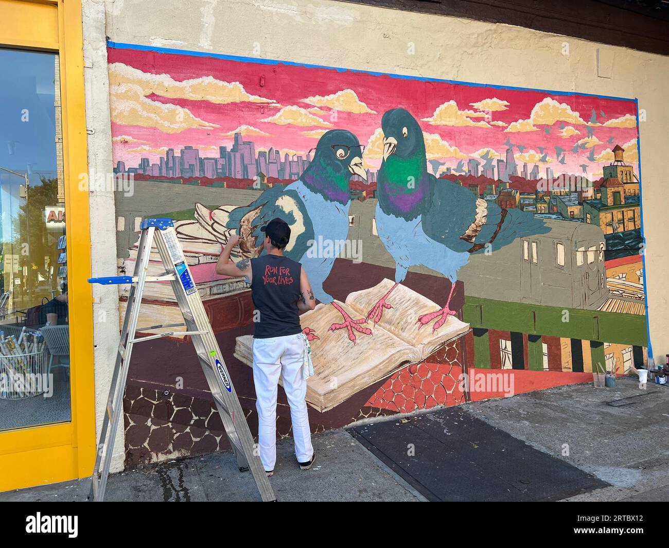 Artist completes a mural on the wall of the new "Lofty Pigeon Books" on ...
