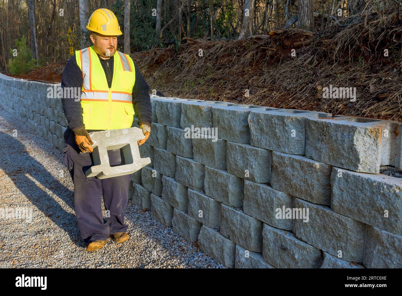 Construction worker lifted concrete block positioned it on retaining ...
