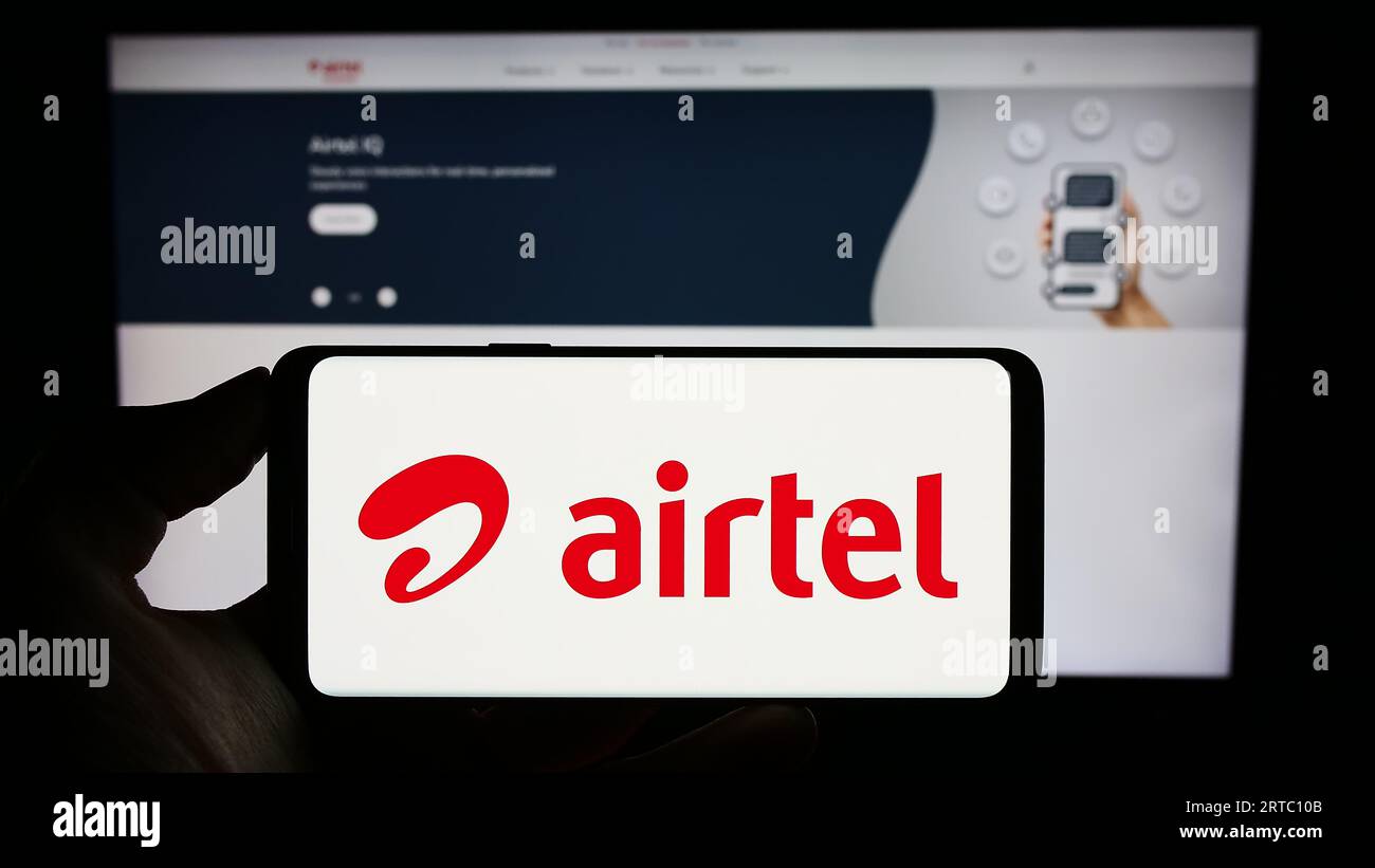 Person holding mobile phone with logo of telecommunications company Bharti Airtel Limited on ...