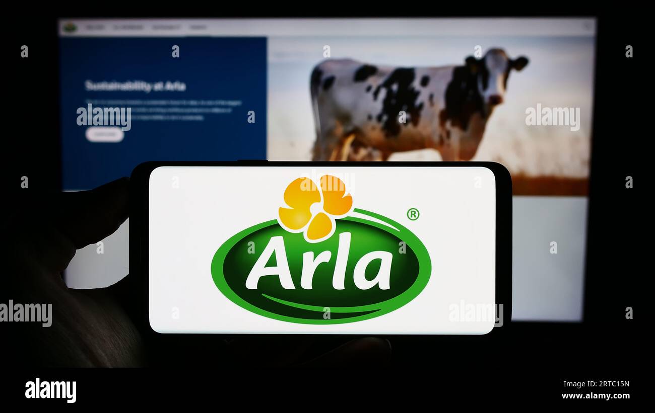 Person holding mobile phone with logo of Nordic dairy company Arla ...