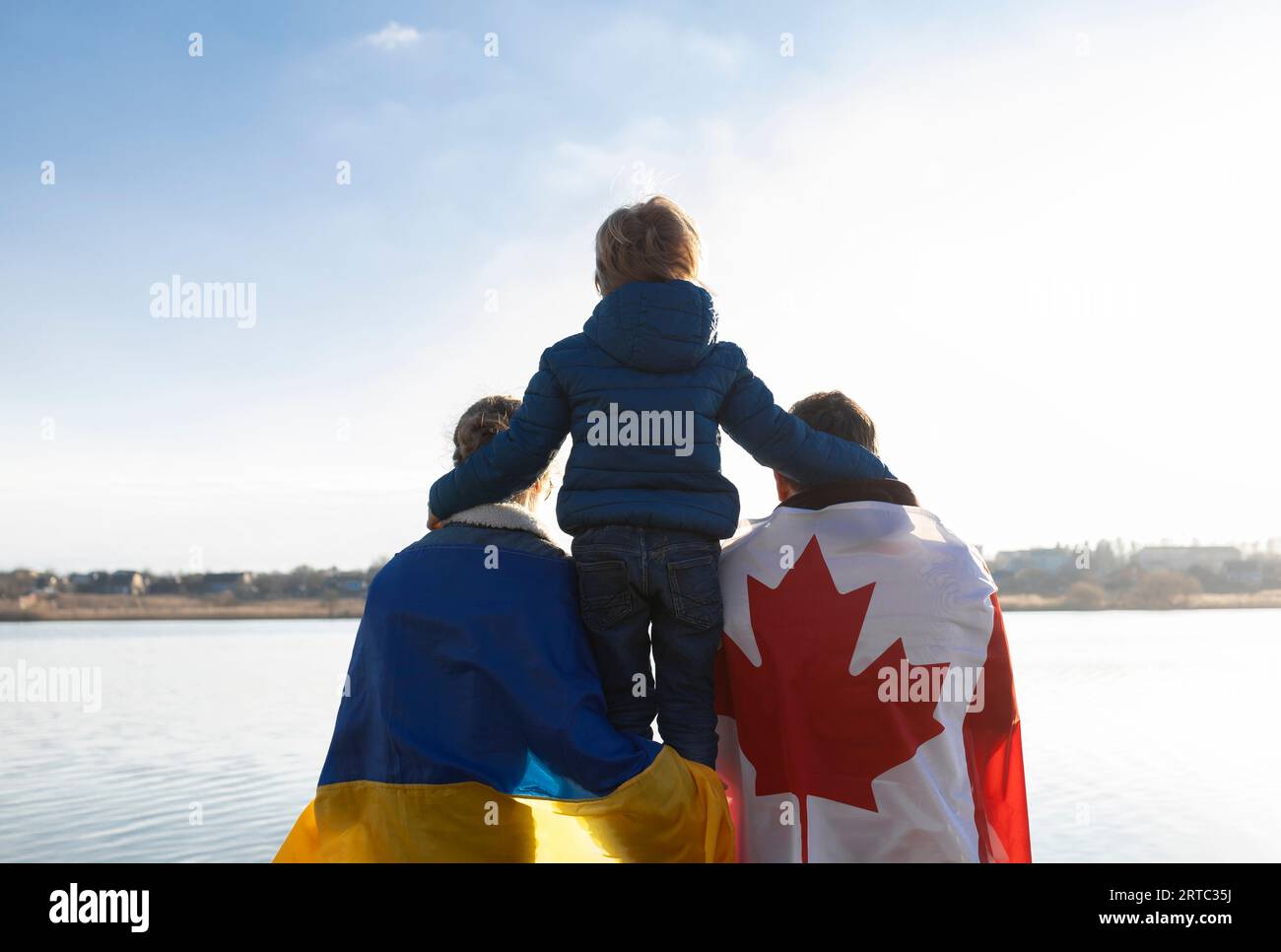 woman with Ukrainian flag, man with Canadian flag behind back and child ...