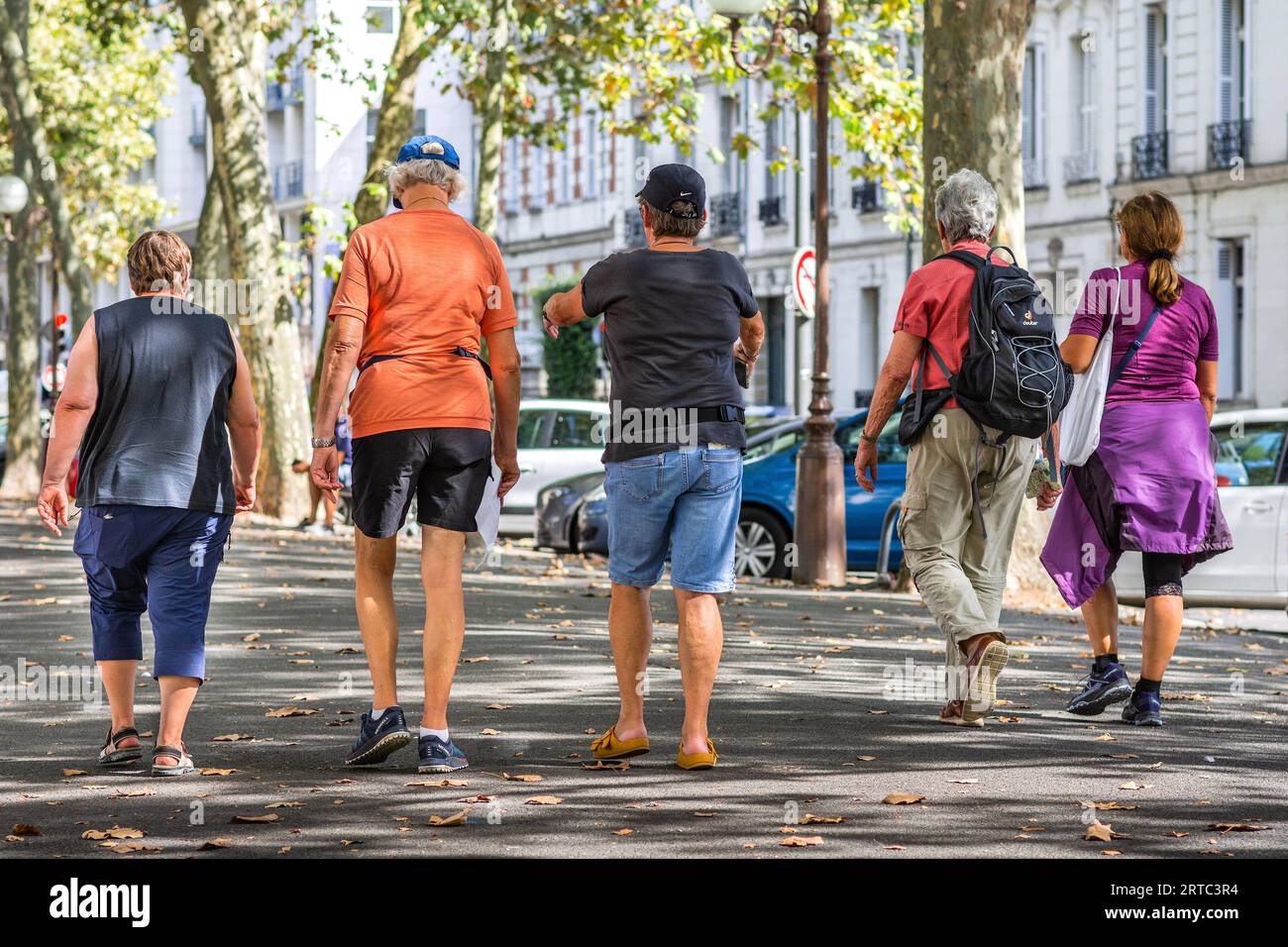 Group of five casually dressed people walking along city center ...