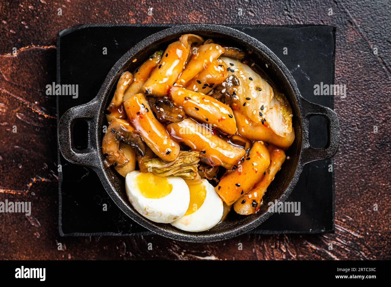 Korean Topokki or Tteokbokki rice cake with egg and mashrooms. Dark ...