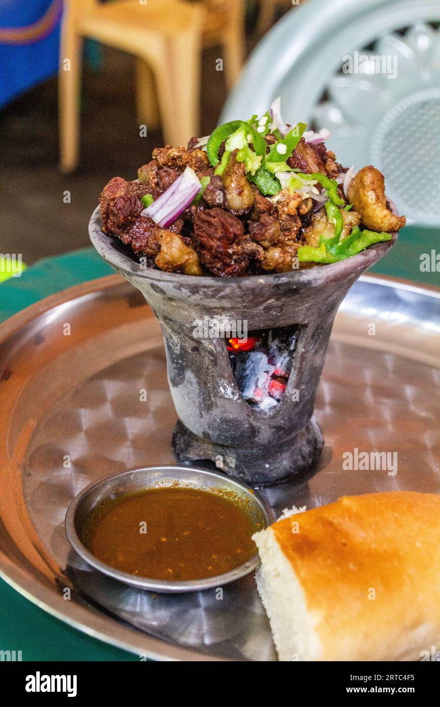 Beef tibs being prepared on a traditional server over hot charcoal in a ...