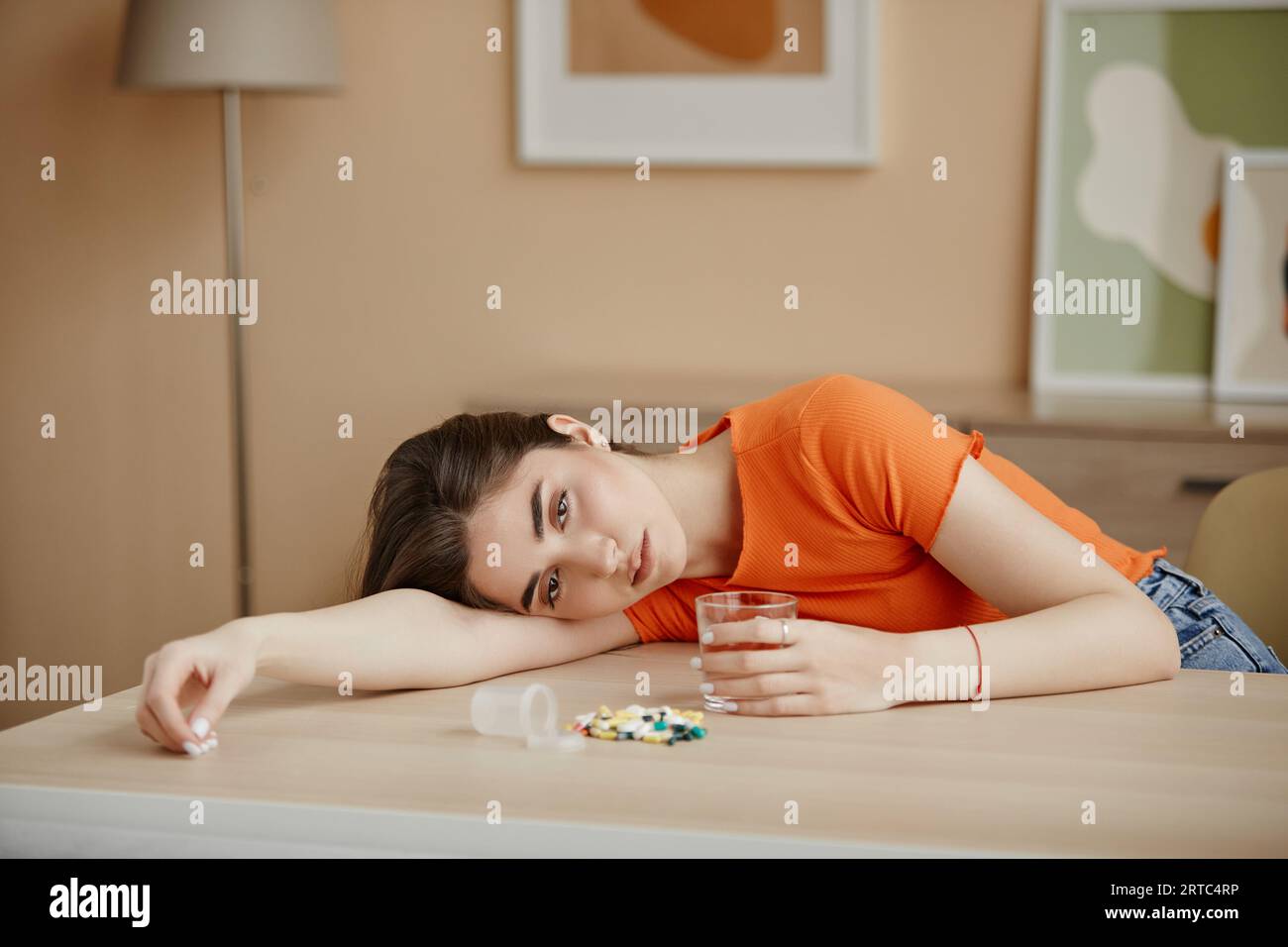 Portrait of depressed young woman staring blankly into space holding ...