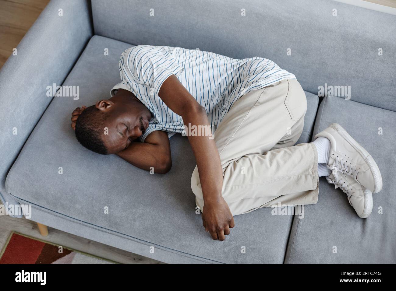 Top view portrait of Black man lying on couch at home curled up in ... Top view portrait of Black man lying on couch at home curled up in ...