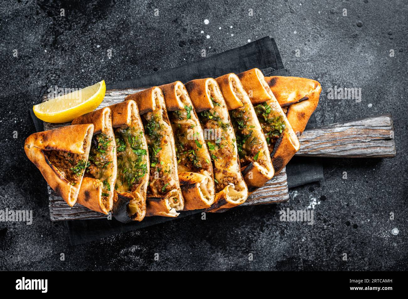 Sliced Turkish flatbread pide, Turkish pizza. Black background. Top ...