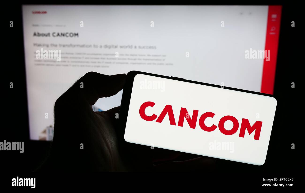 Person holding smartphone with logo of German information technology company Cancom SE on screen ...
