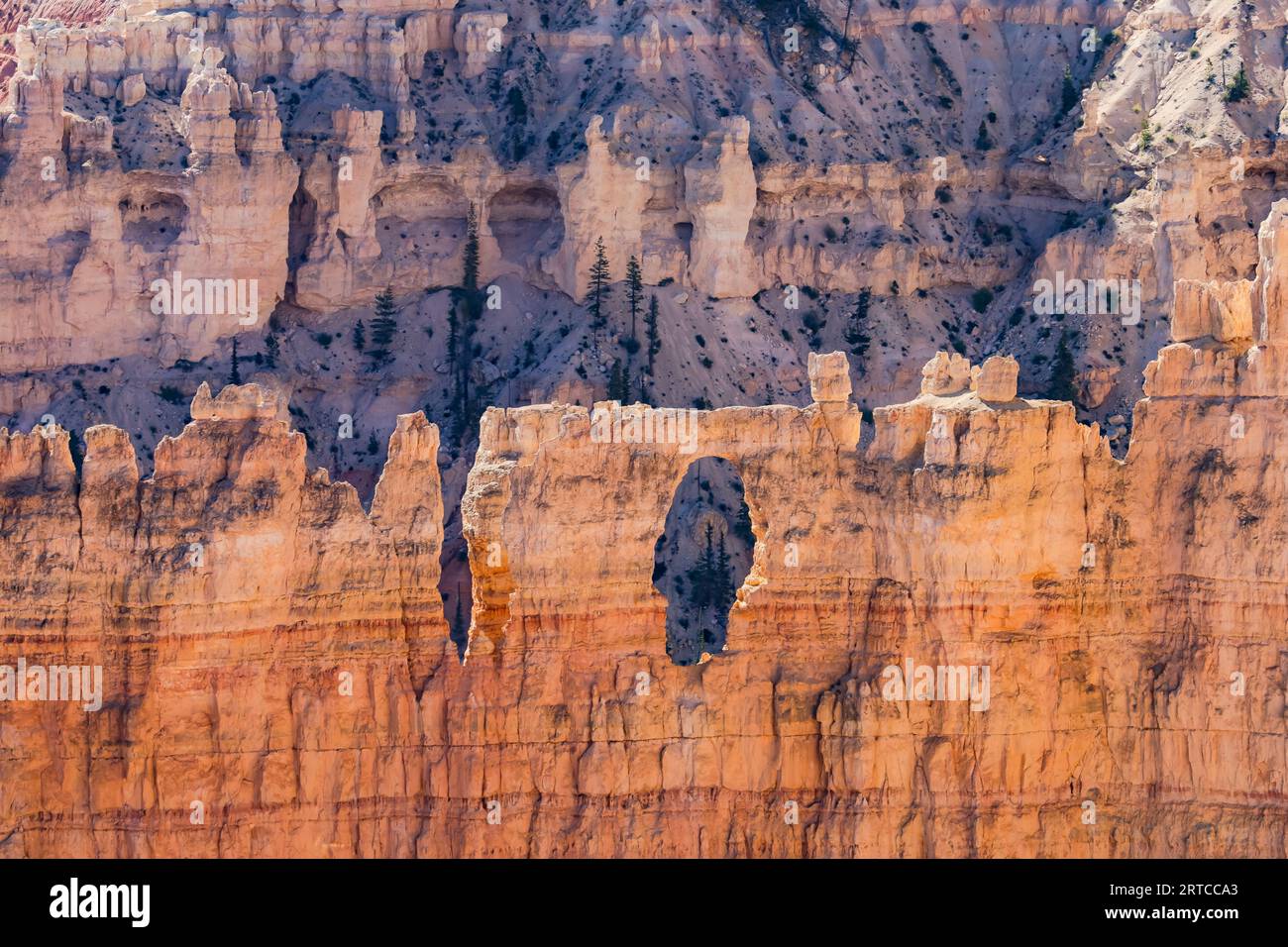 Prominent rock face with a hole in front of the rock formations of ...