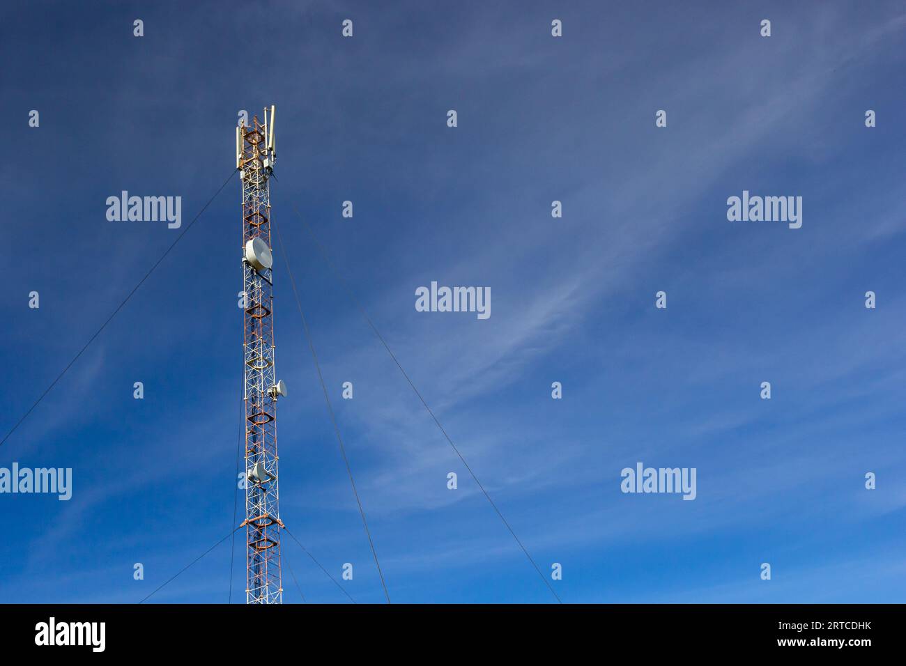 Telecommunication tower for mobile phone with antennas over a blue sky. Distribution function of ...
