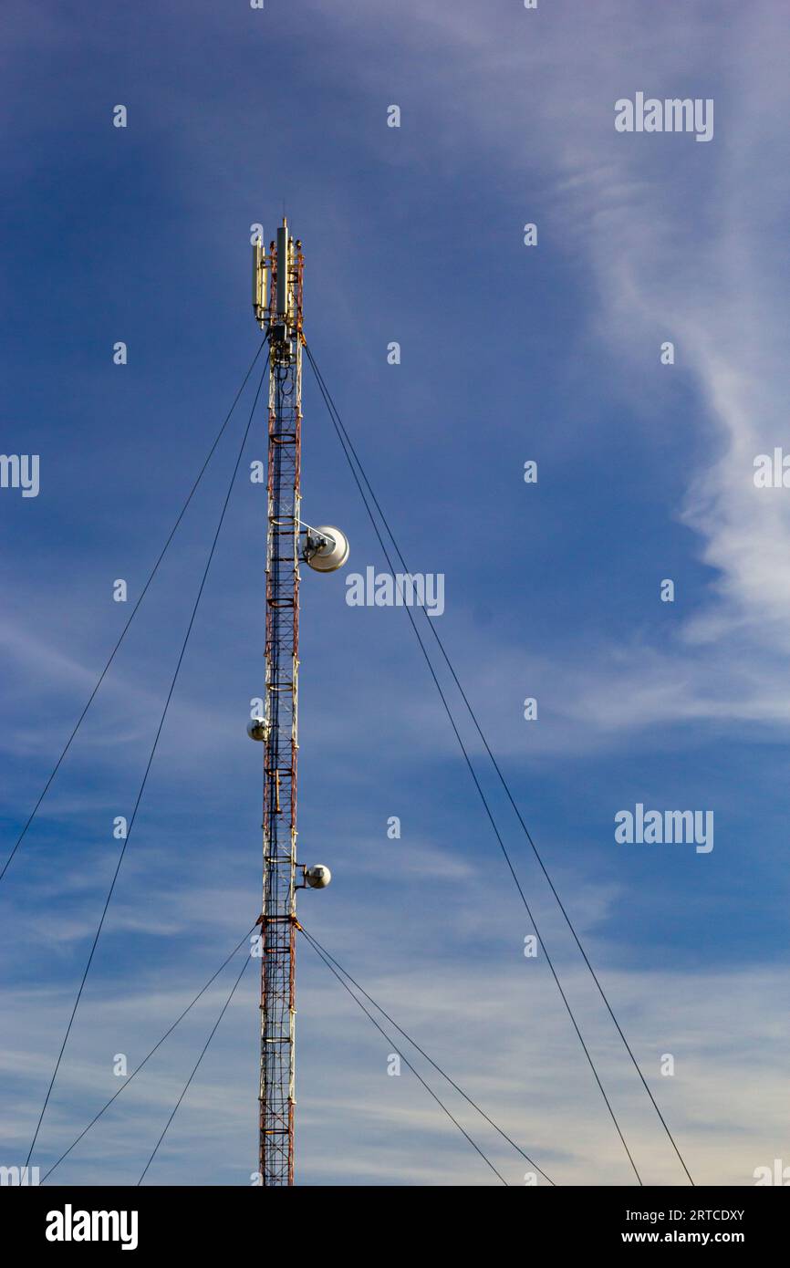 Telecommunication tower for mobile phone with antennas over a blue sky. Distribution function of ...
