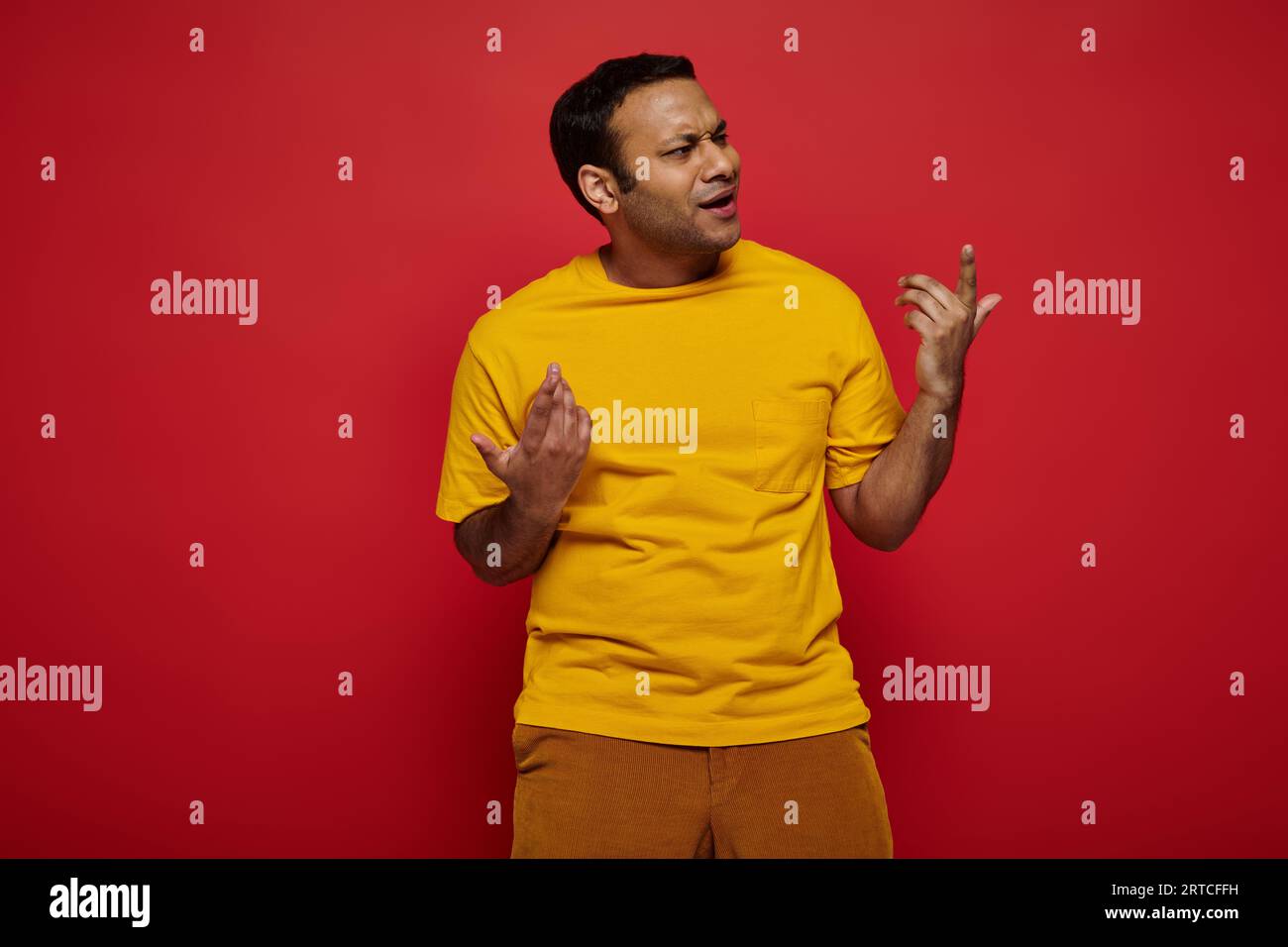 emotional indian man in bright casual clothes gesturing while ...
