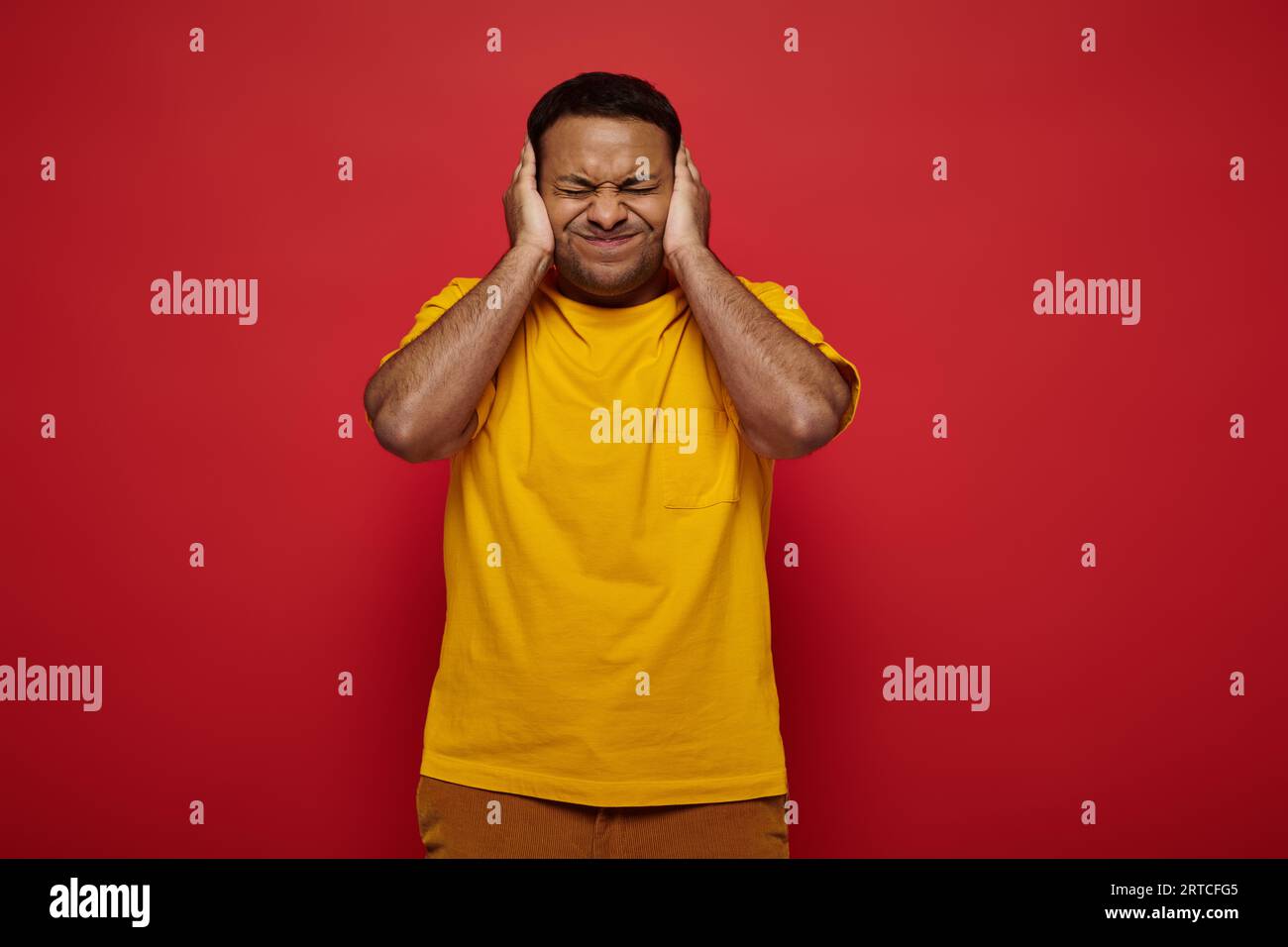 tensed indian man in bright clothes standing with closed eyes and ...