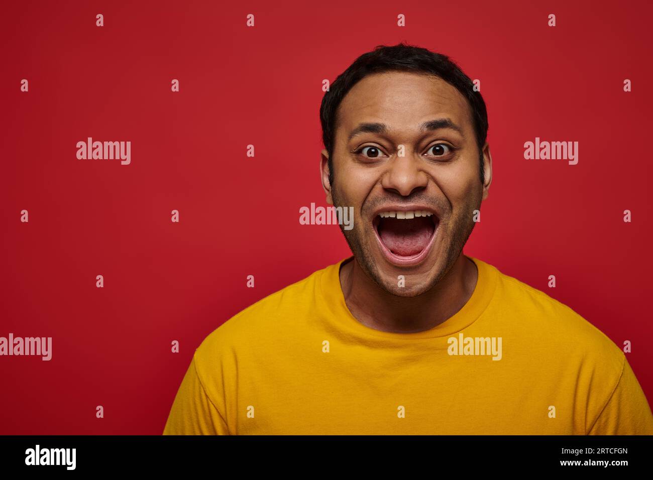 positive emotion, excited indian man in yellow t-shirt with opened ...