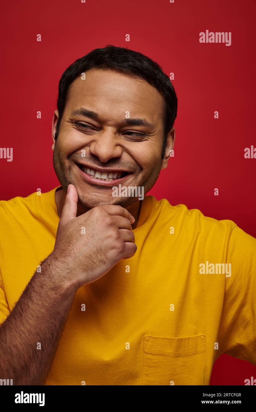 positive emotion, joyful indian man in yellow t-shirt smiling and ...