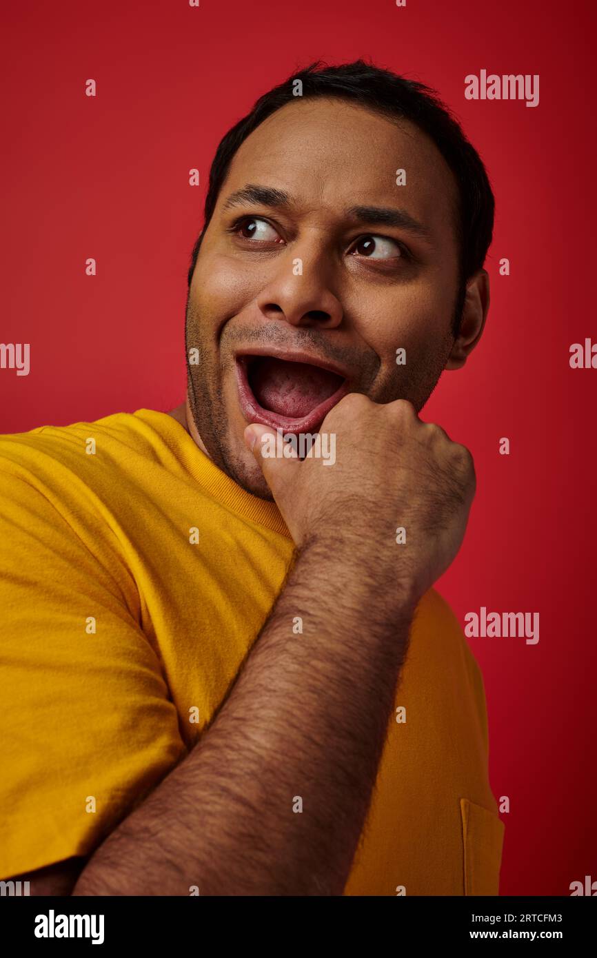 wow expression, amazed indian man in yellow t-shirt looking away with ...