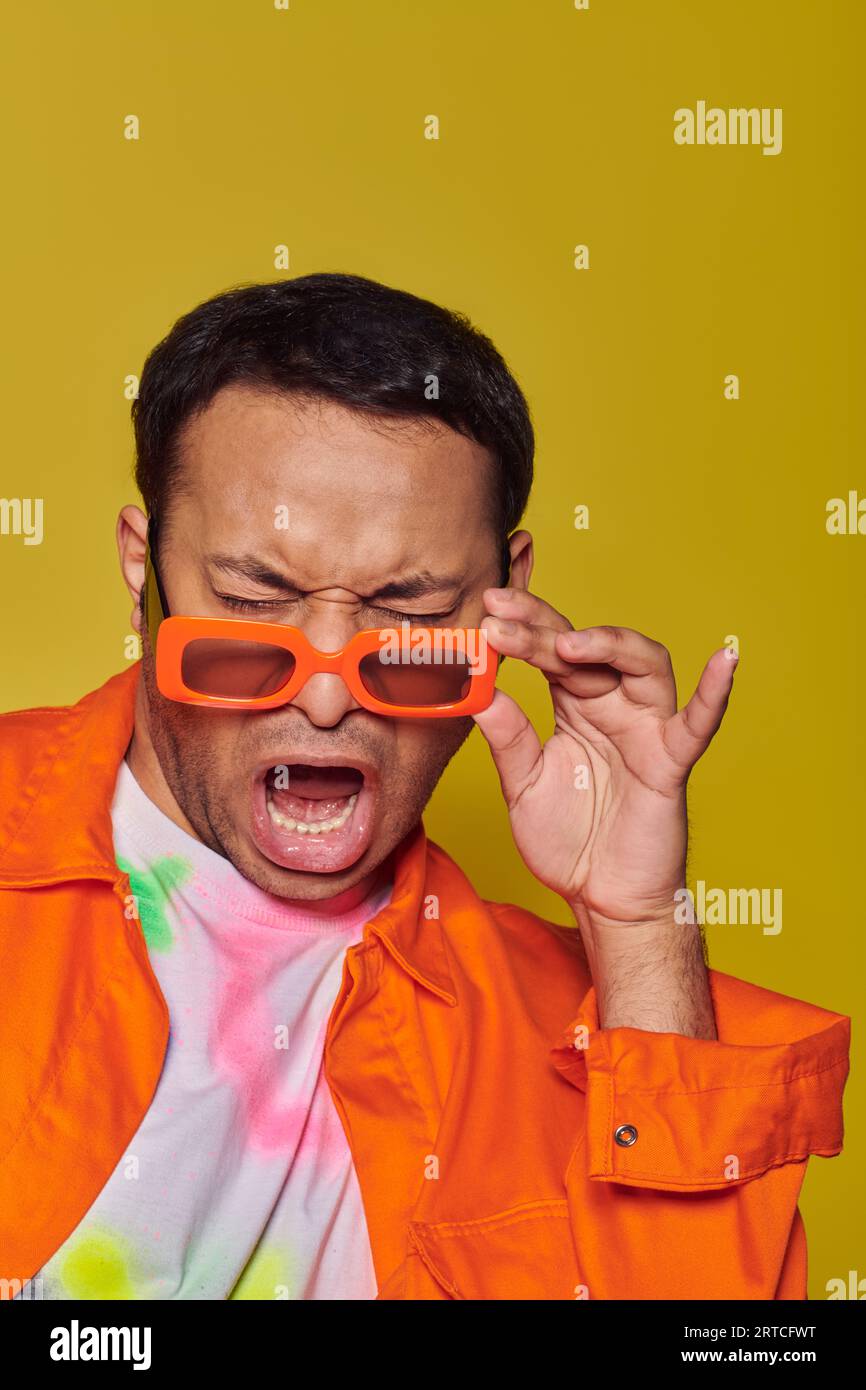 face expression, indian man adjusting orange sunglasses and grimacing ...