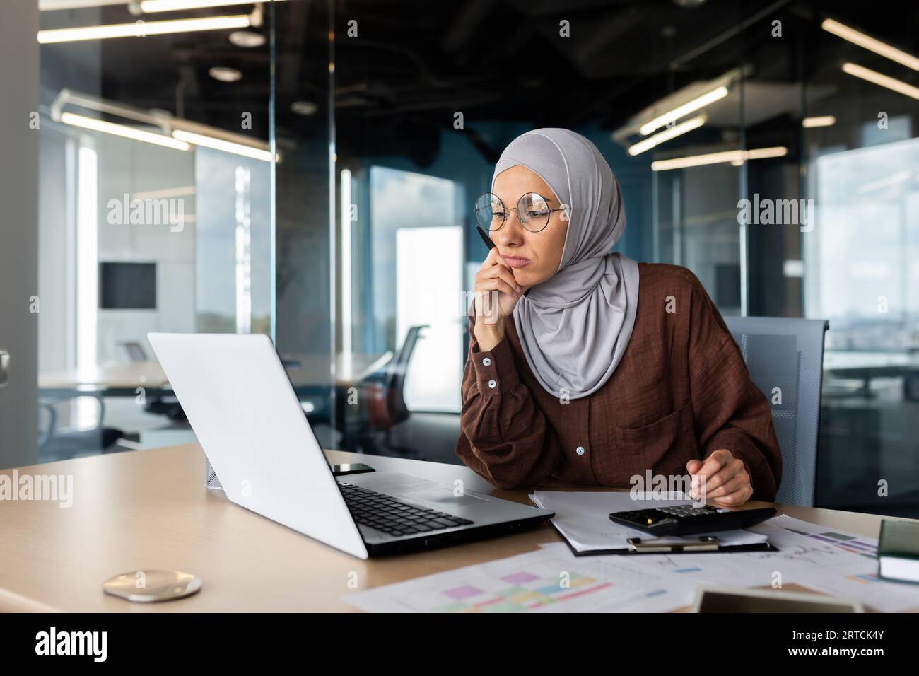 Tired young Muslim woman in hijab is sitting in the office at the desk ...