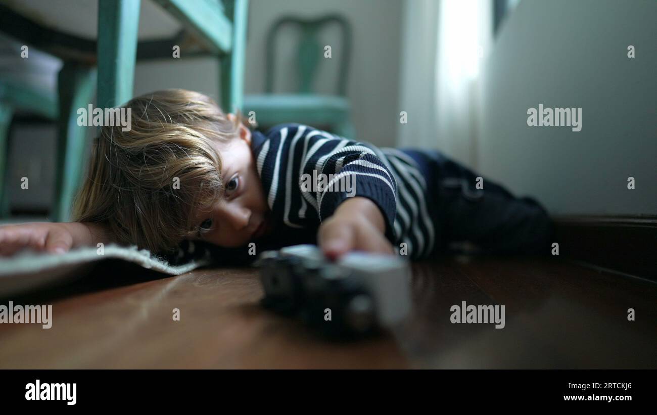 Child playing by himself on floor at home, one little boy engaged with ...