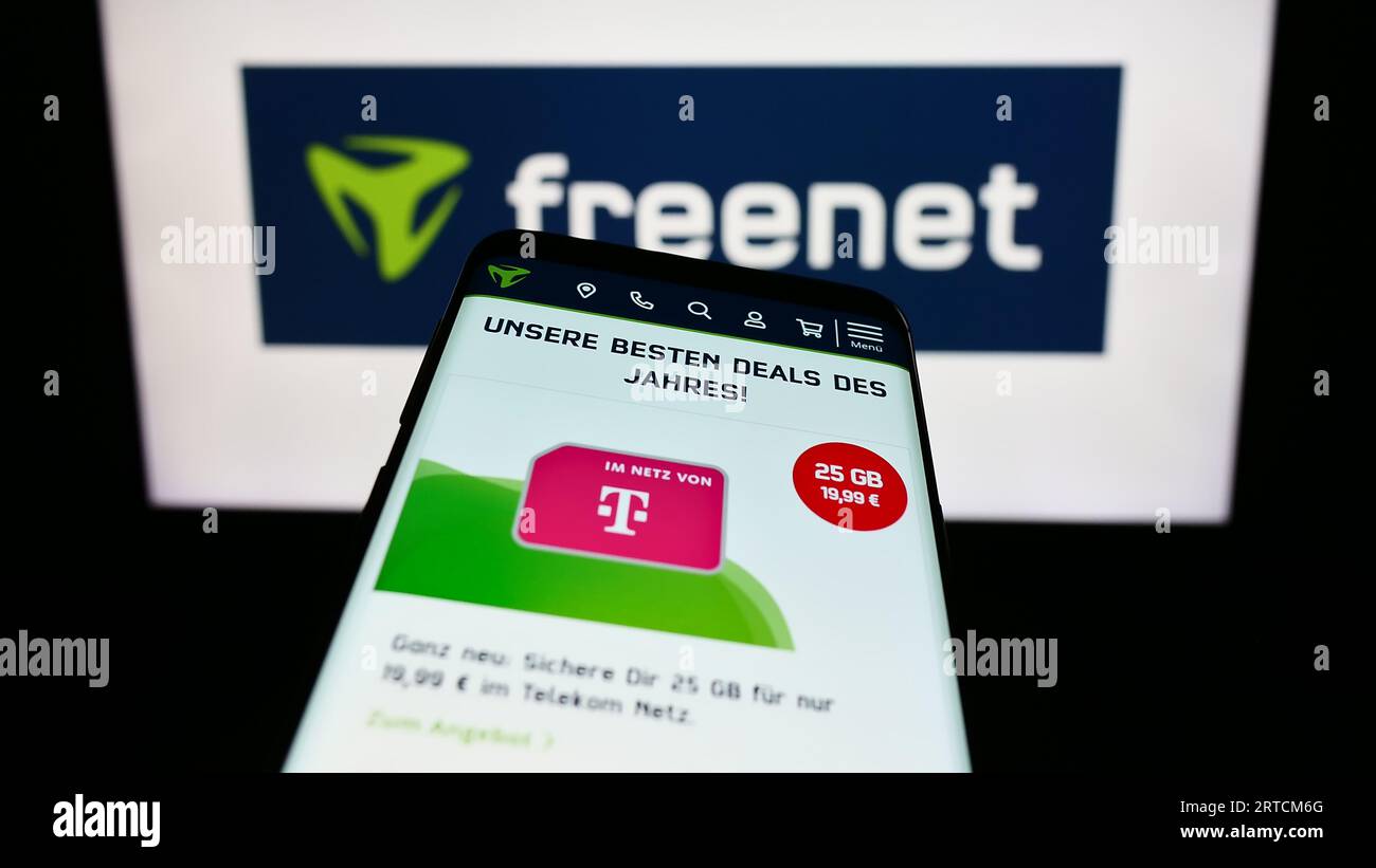 Mobile phone with website of German telecommunications company Freenet AG on screen in front of ...