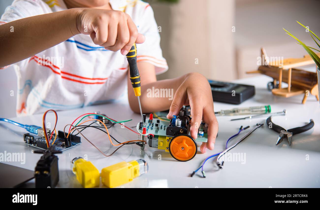 Asian kid boy assembling the Arduino robot car homework project at home ...