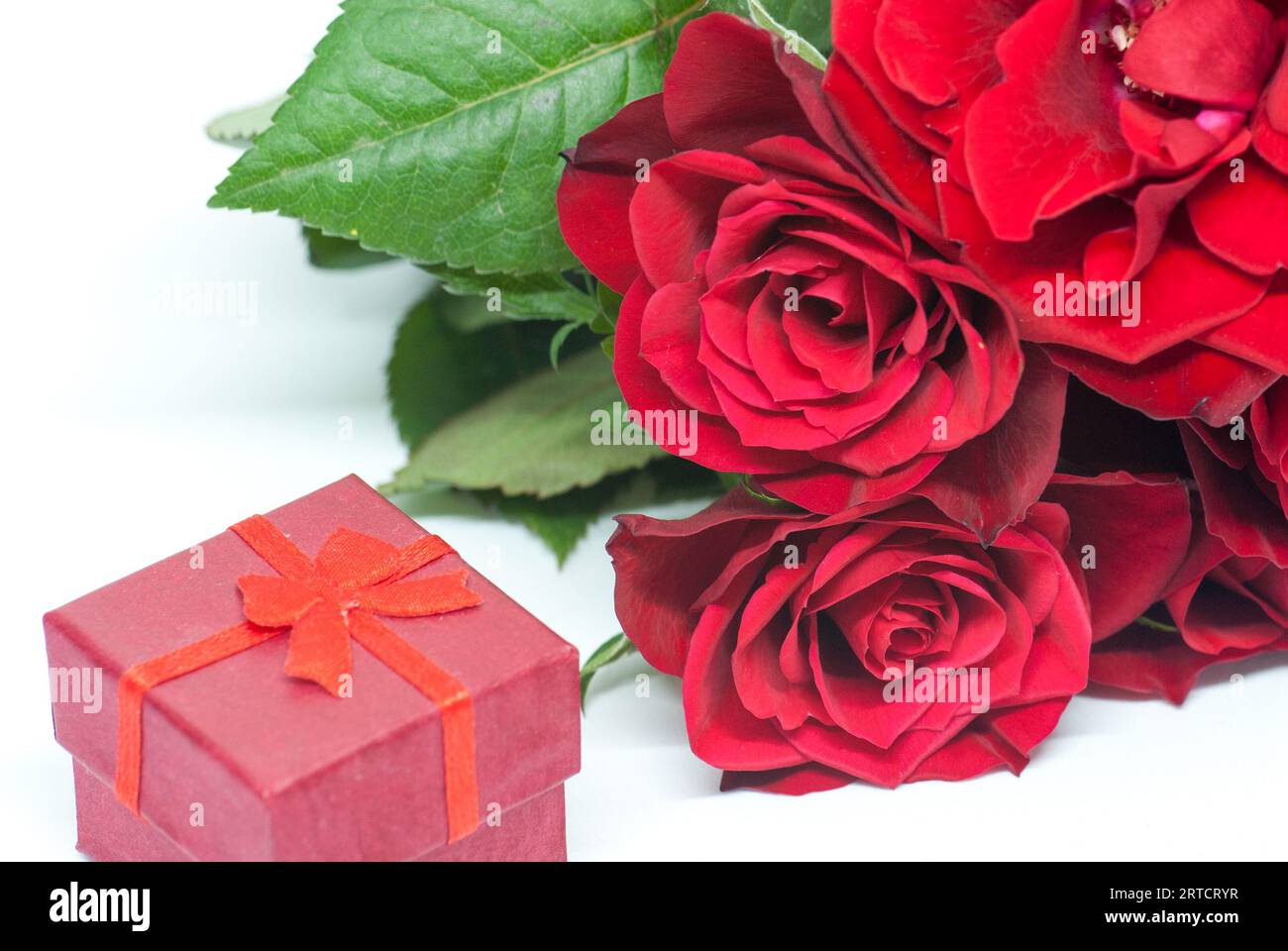 Red roses bouquet and small wedding engagement ring box on white space ...