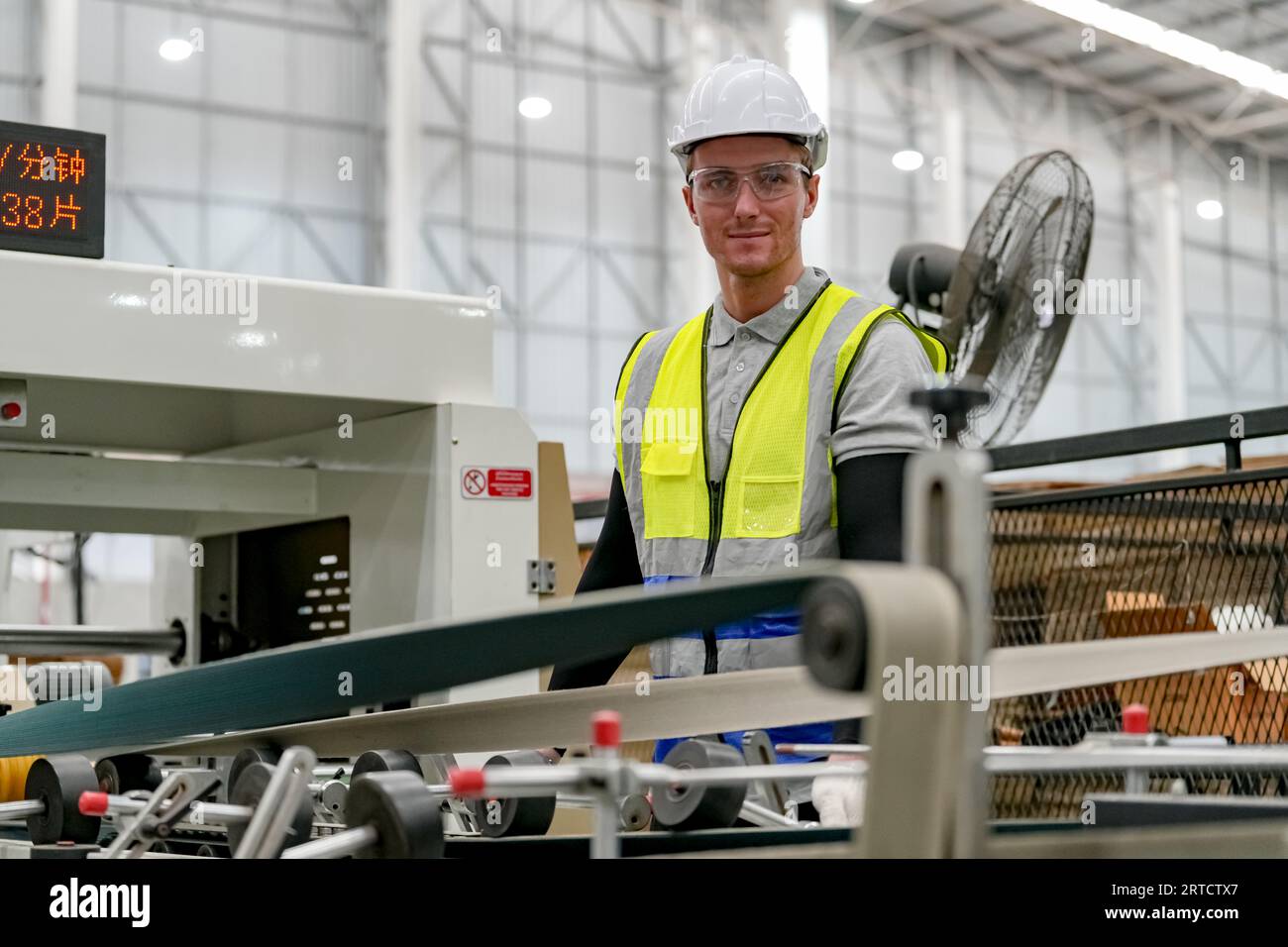 Industrial worker indoors in factory. Young technician with orange hard ...