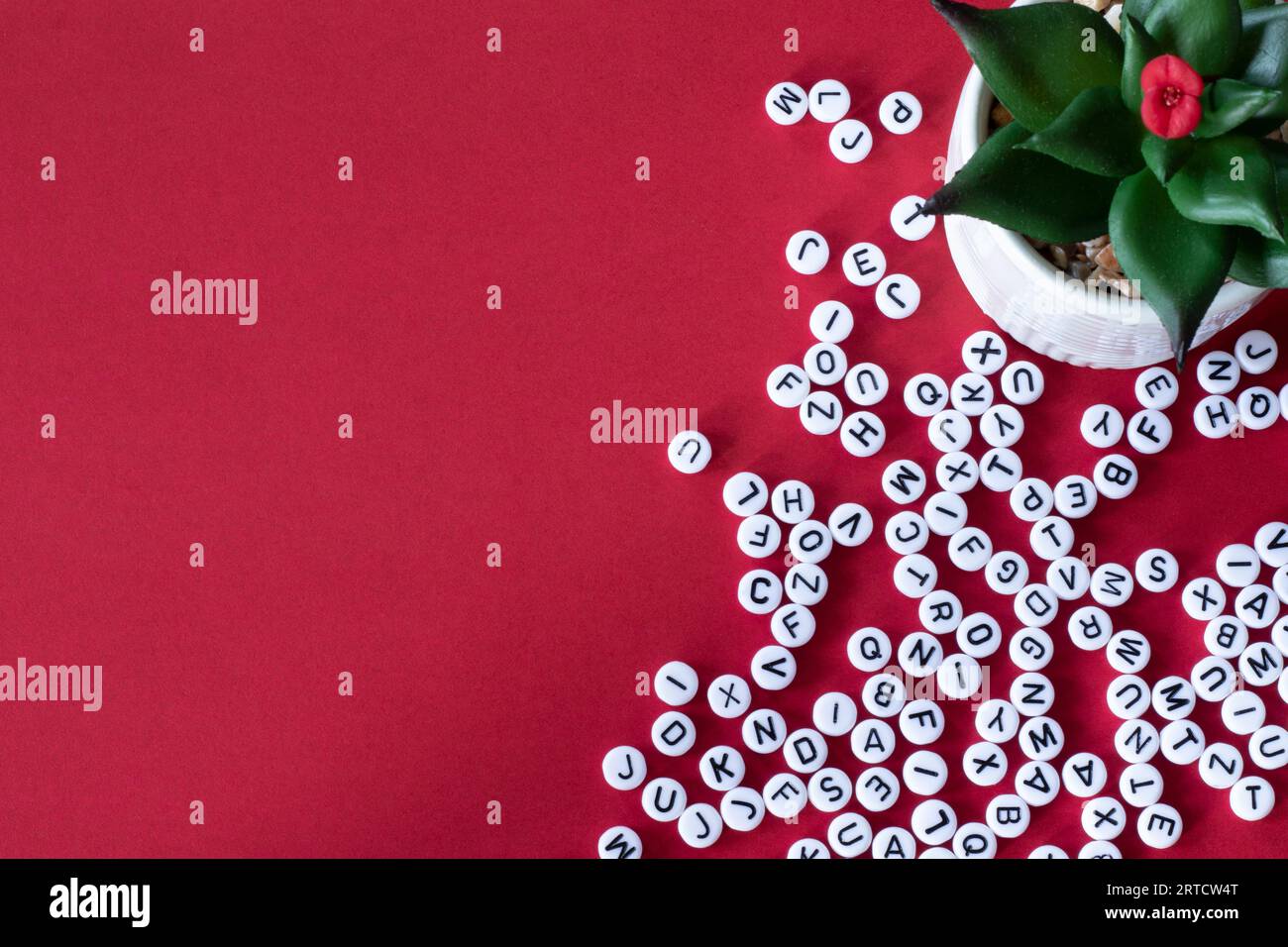 Letter beads spilled on a red background with copy space. Top view ...