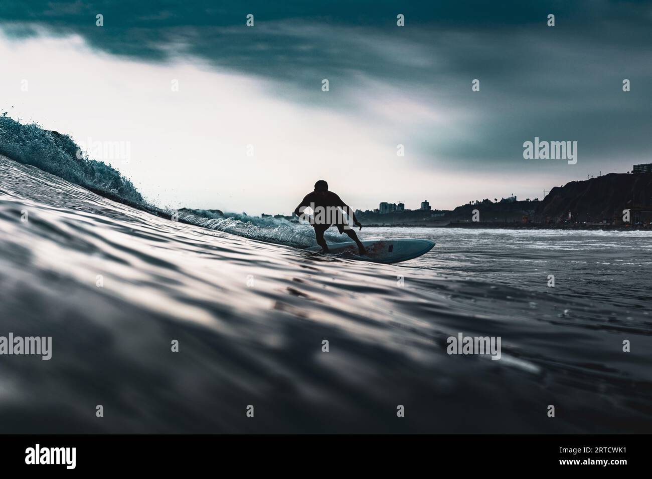 Surfer riding a wave with city background in the afternoon Stock Photo ...