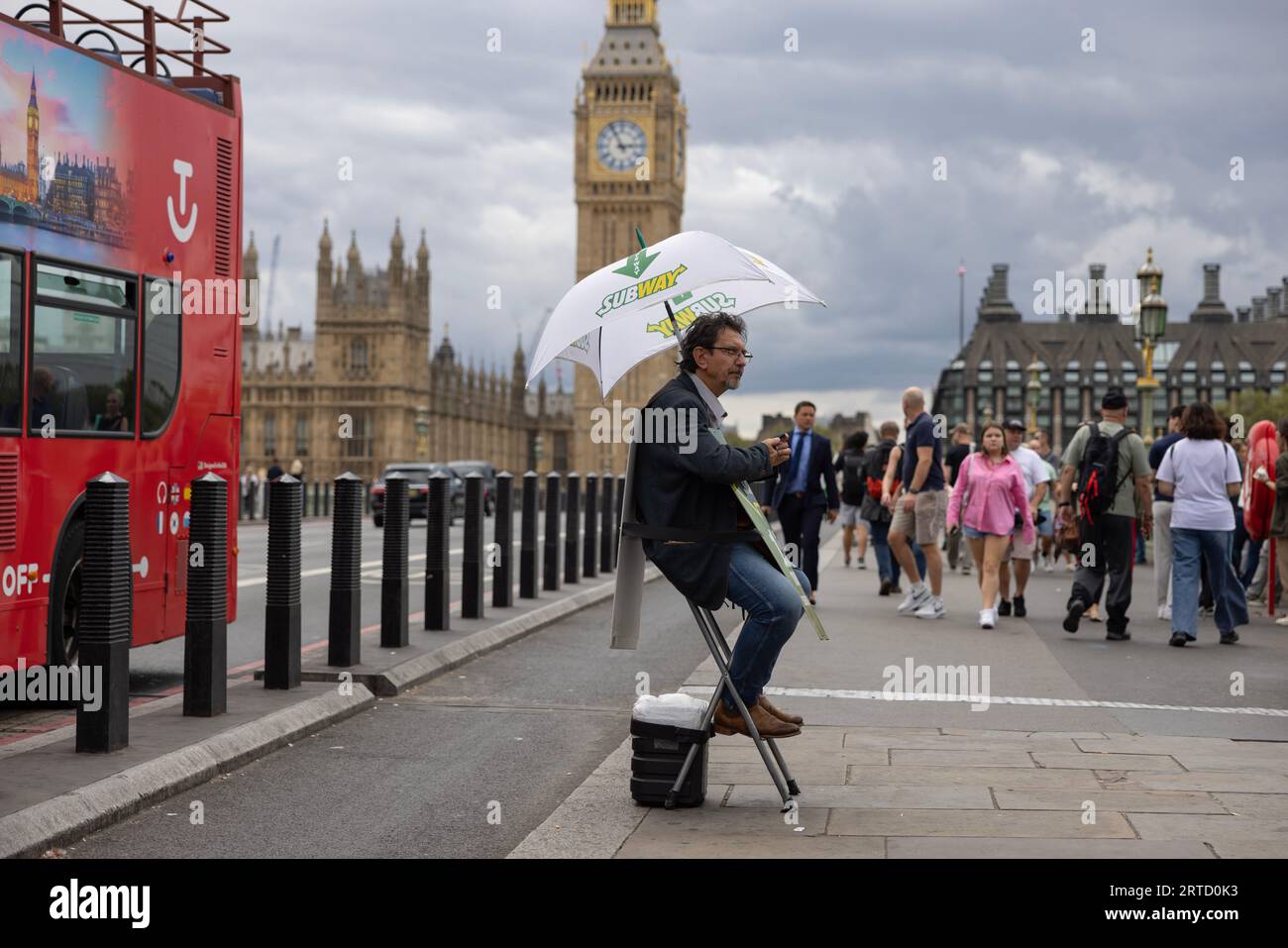 Man sitting on a folding chair promoting and giving directions to ...