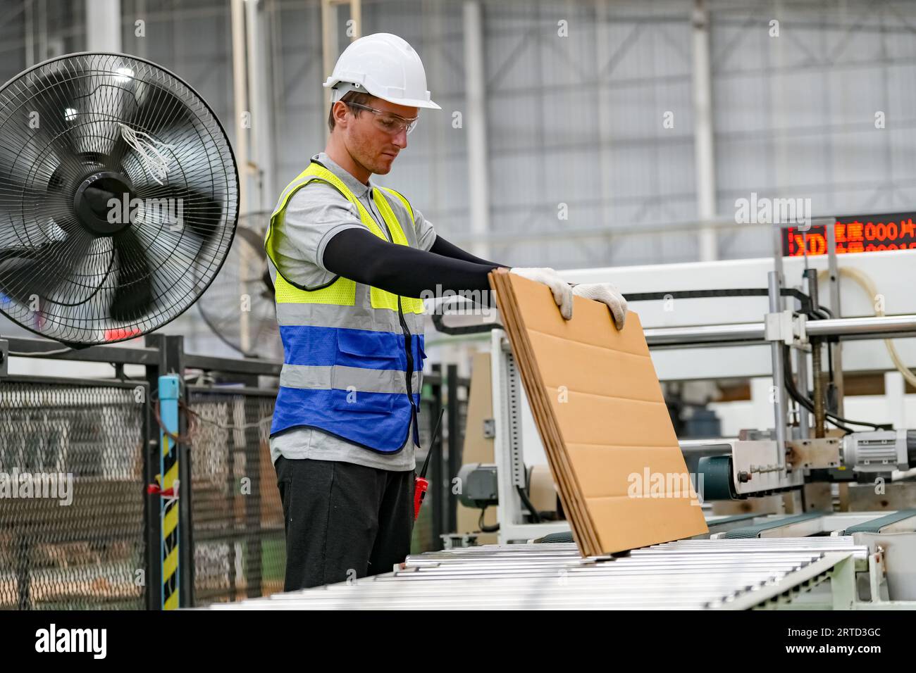 Industrial worker indoors in factory. Young technician with orange hard ...