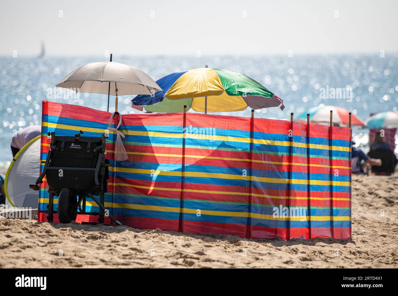family sitting on a beach behind a windbreak with shadows and ...