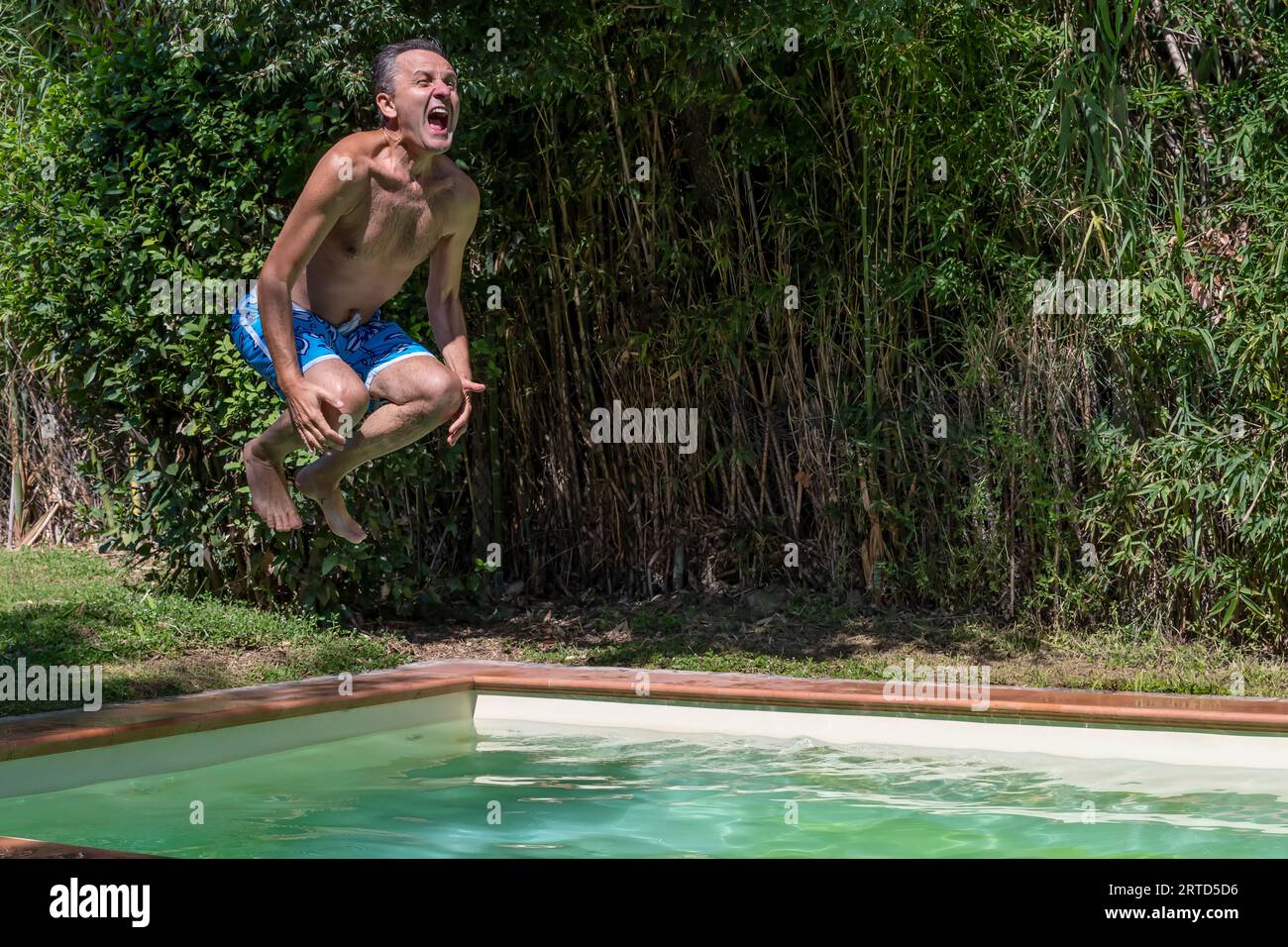 Middle-aged white man dives into the pool cannonball style, with a ...